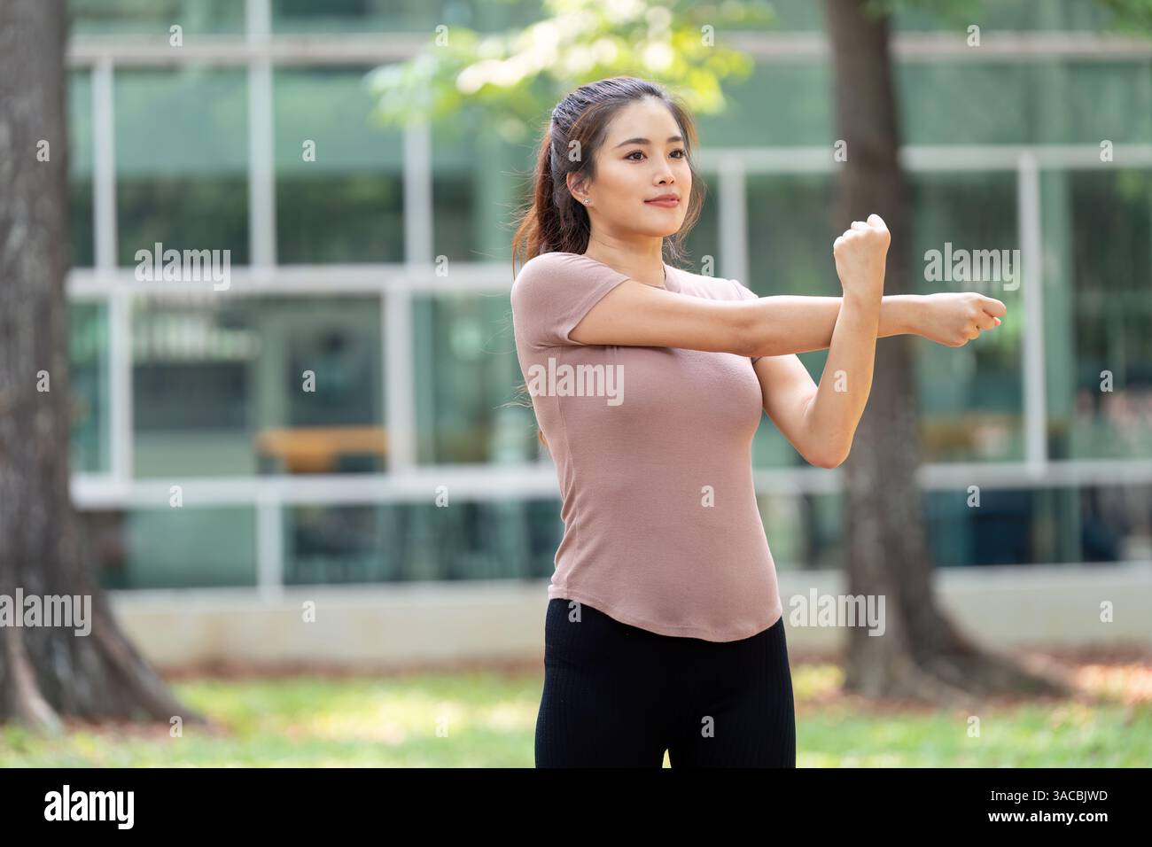 Stretching and Fitness. A woman engages in arm stretches outdoors to enhance flexibility and ...