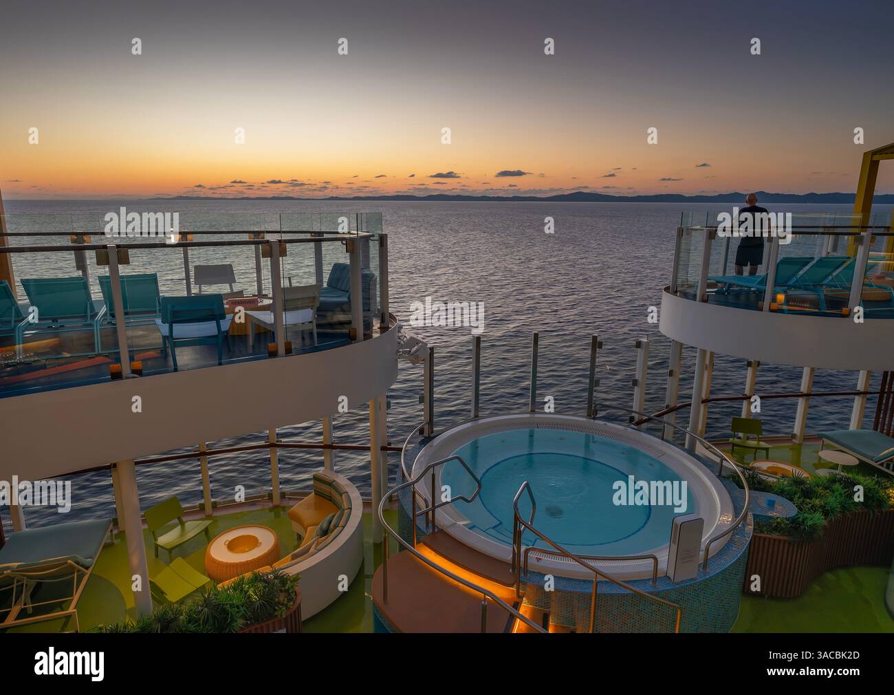 Man watches Roatan sunrise while standing on a deck with chairs and ...