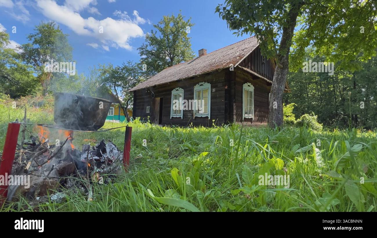 Cooking in cauldron on burning campfire near old wooden house in ...