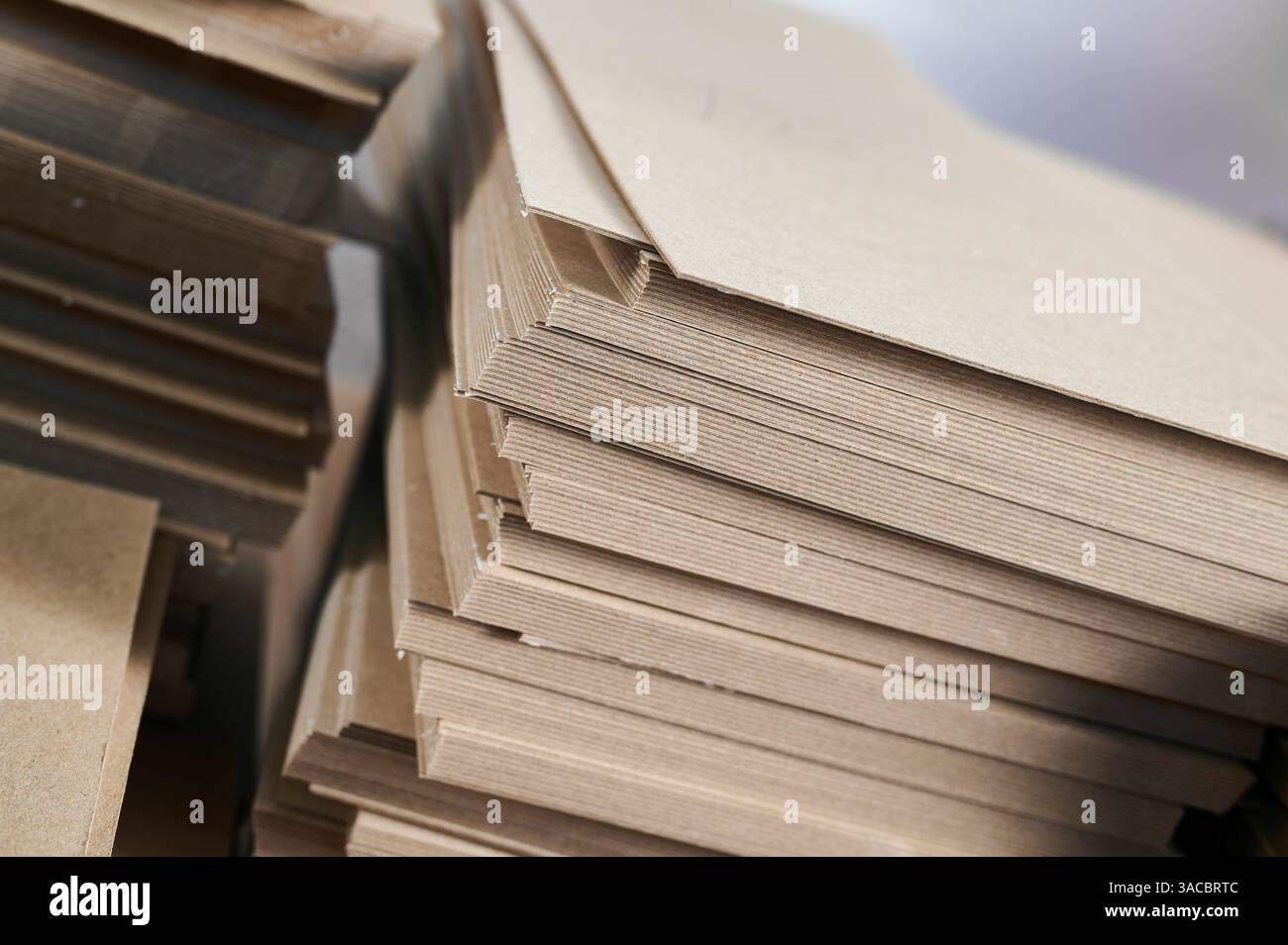 Stacks of thick paperboard await processing into sturdy cardboard boxes ...