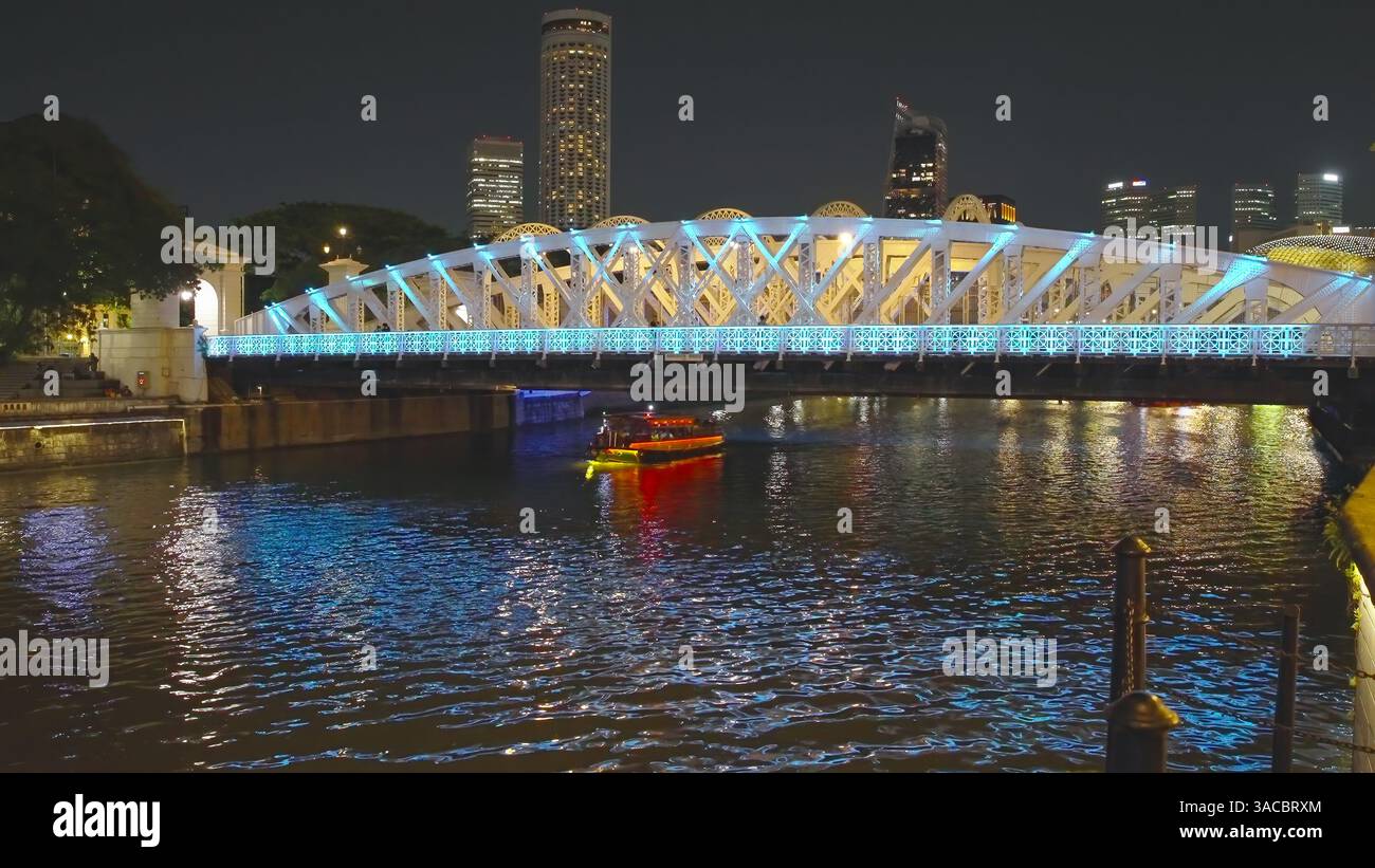 a night shot of a boat passing under anderson bridge and the singapore ...