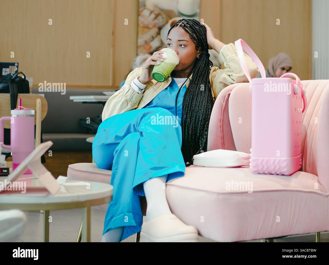 A black woman in a nurse's uniform drinks macha tea in Elkins Park ...