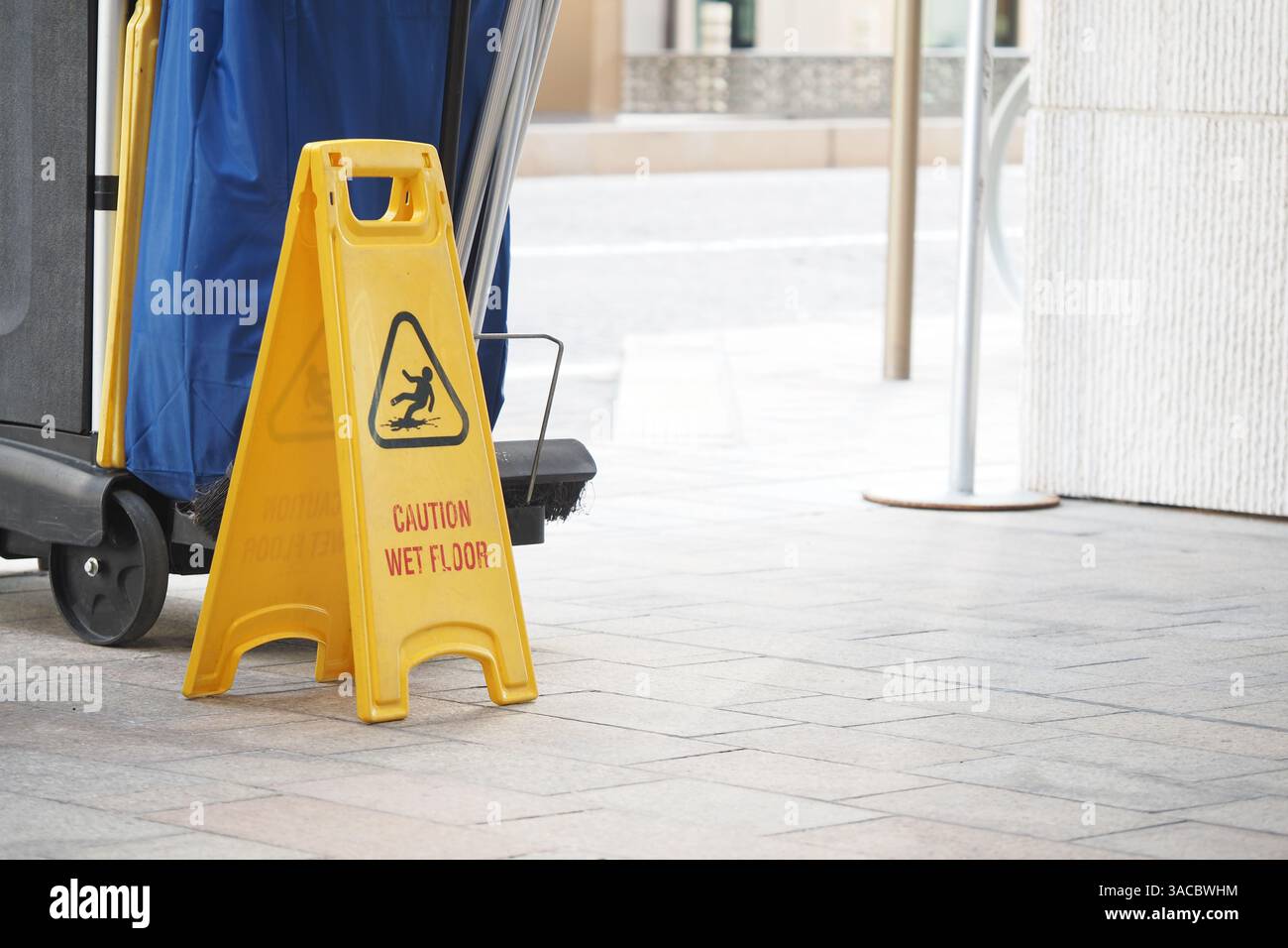 Caution sign indicating wet floor near cleaning equipment outside Stock ...