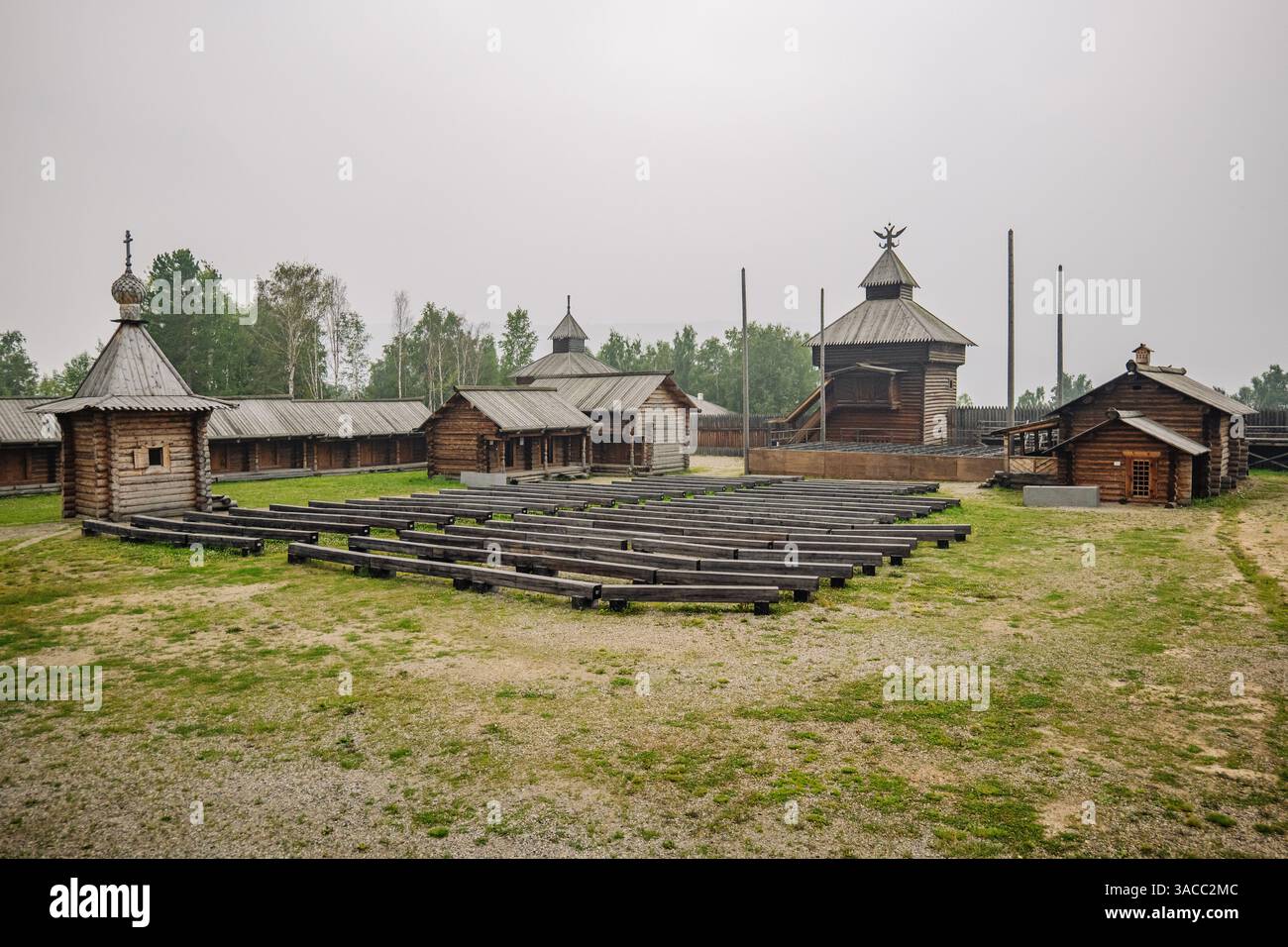 Rows of wooden benches filling a grassy area in front of historic log ...