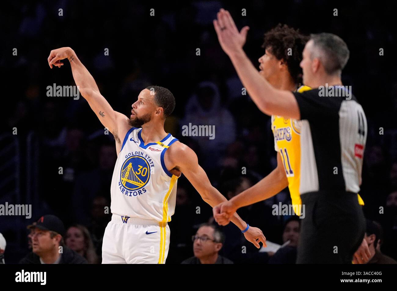 Golden State Warriors guard Stephen Curry, left, watches along with Los Angeles Lakers center ...