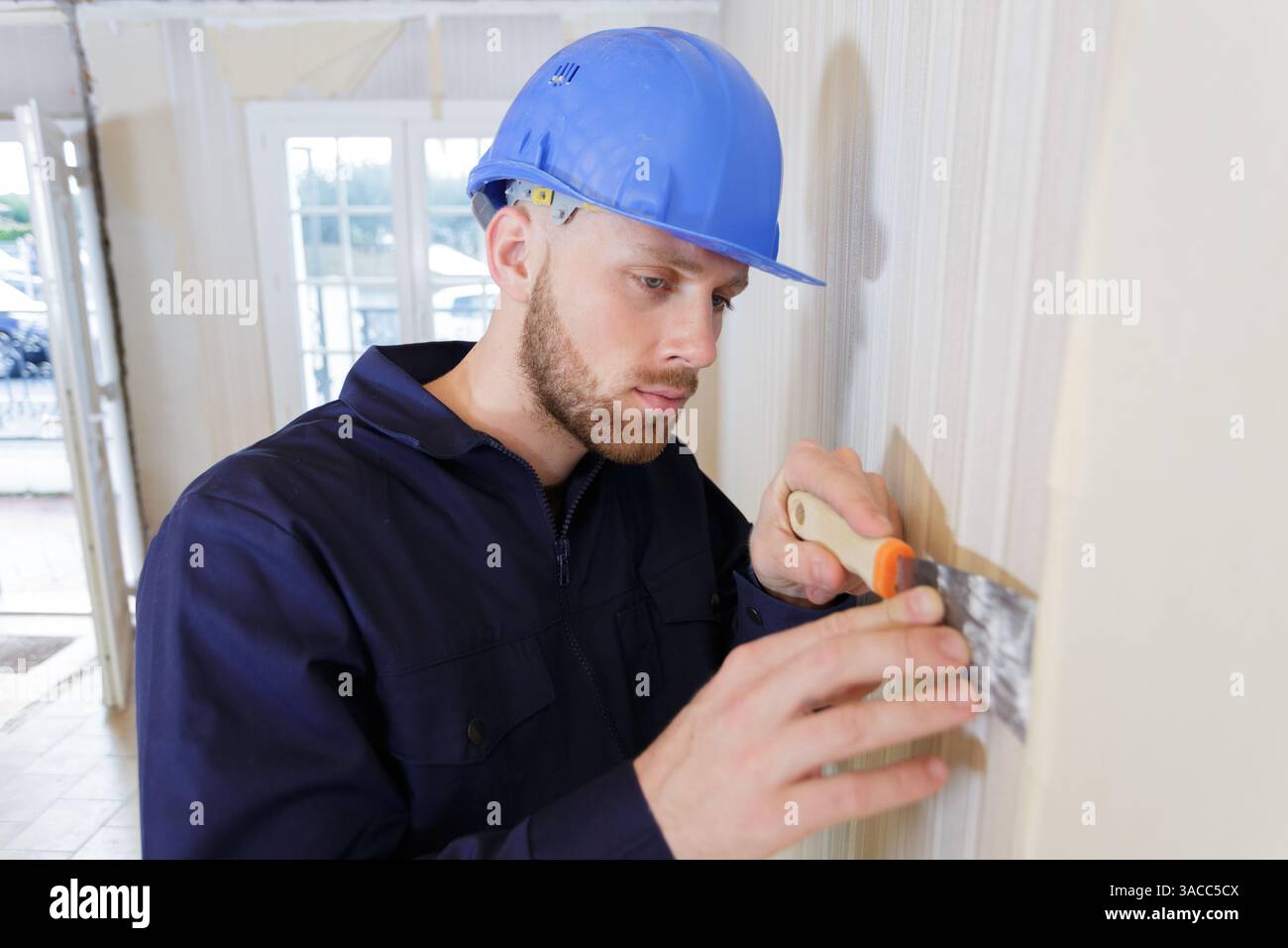 man removing plaster from wall indoors Stock Photo - Alamy