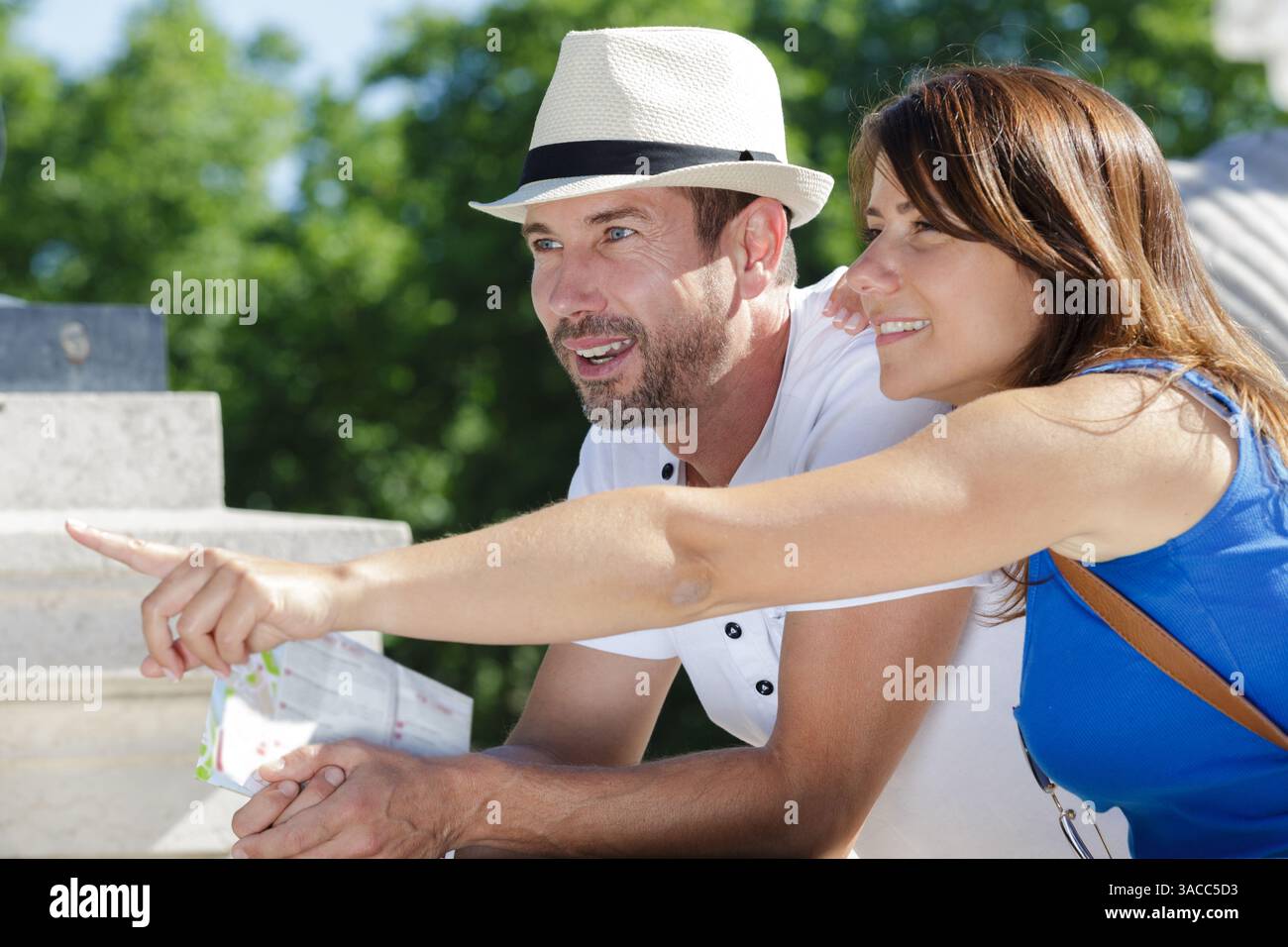 couple with tourist map pointing into distance Stock Photo - Alamy