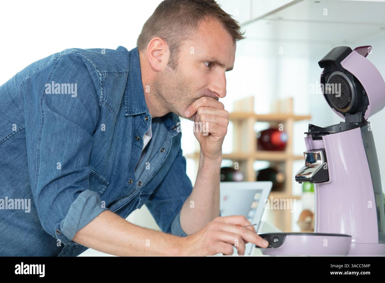 serious man repairing broken coffee machine Stock Photo - Alamy