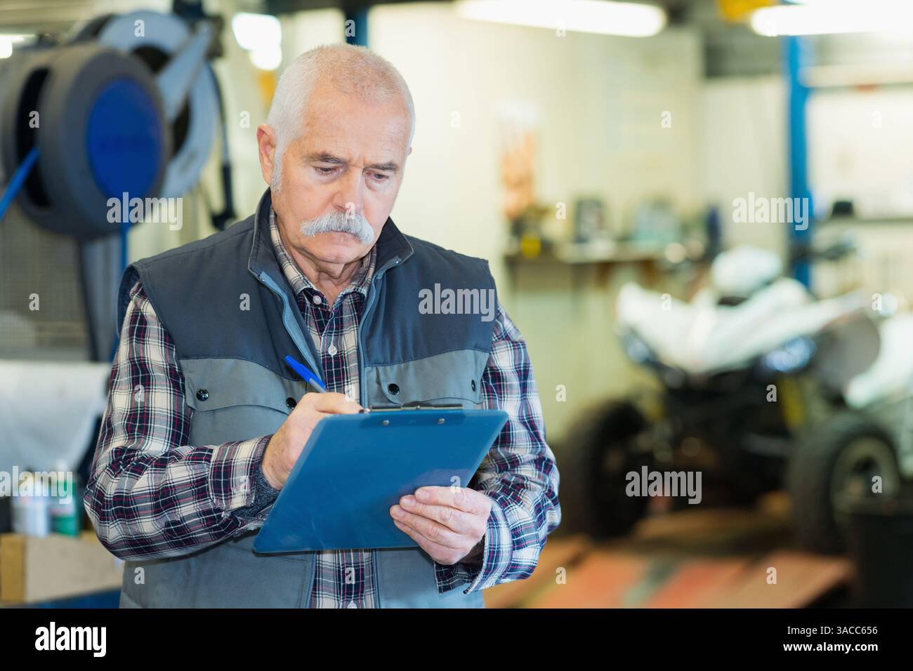 elderly mechanic checking quad vehicle Stock Photo - Alamy
