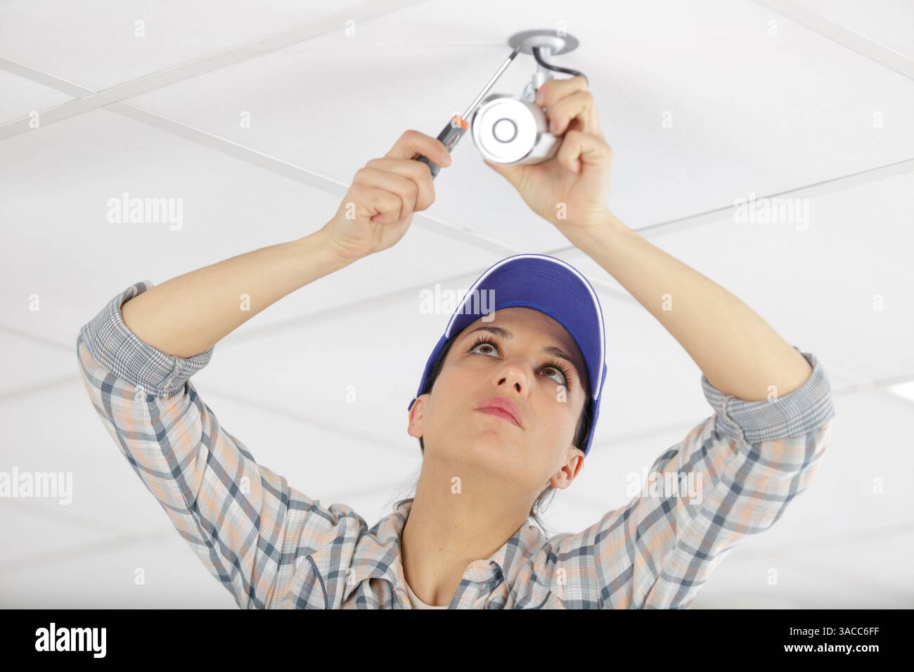 female worker changing spotlight on the ceiling Stock Photo - Alamy