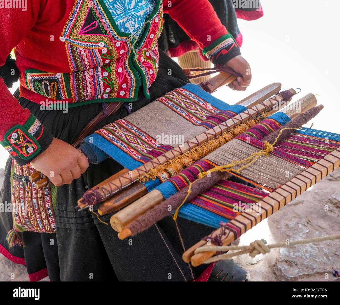 An artisan near Cusco, Peru, weaves a traditional textile using a ...