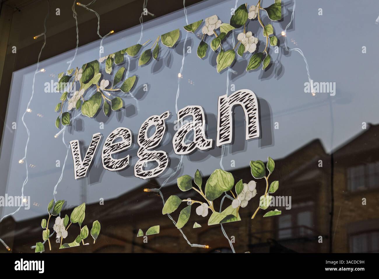 Vegan window display with leafy design and string lights in city ...