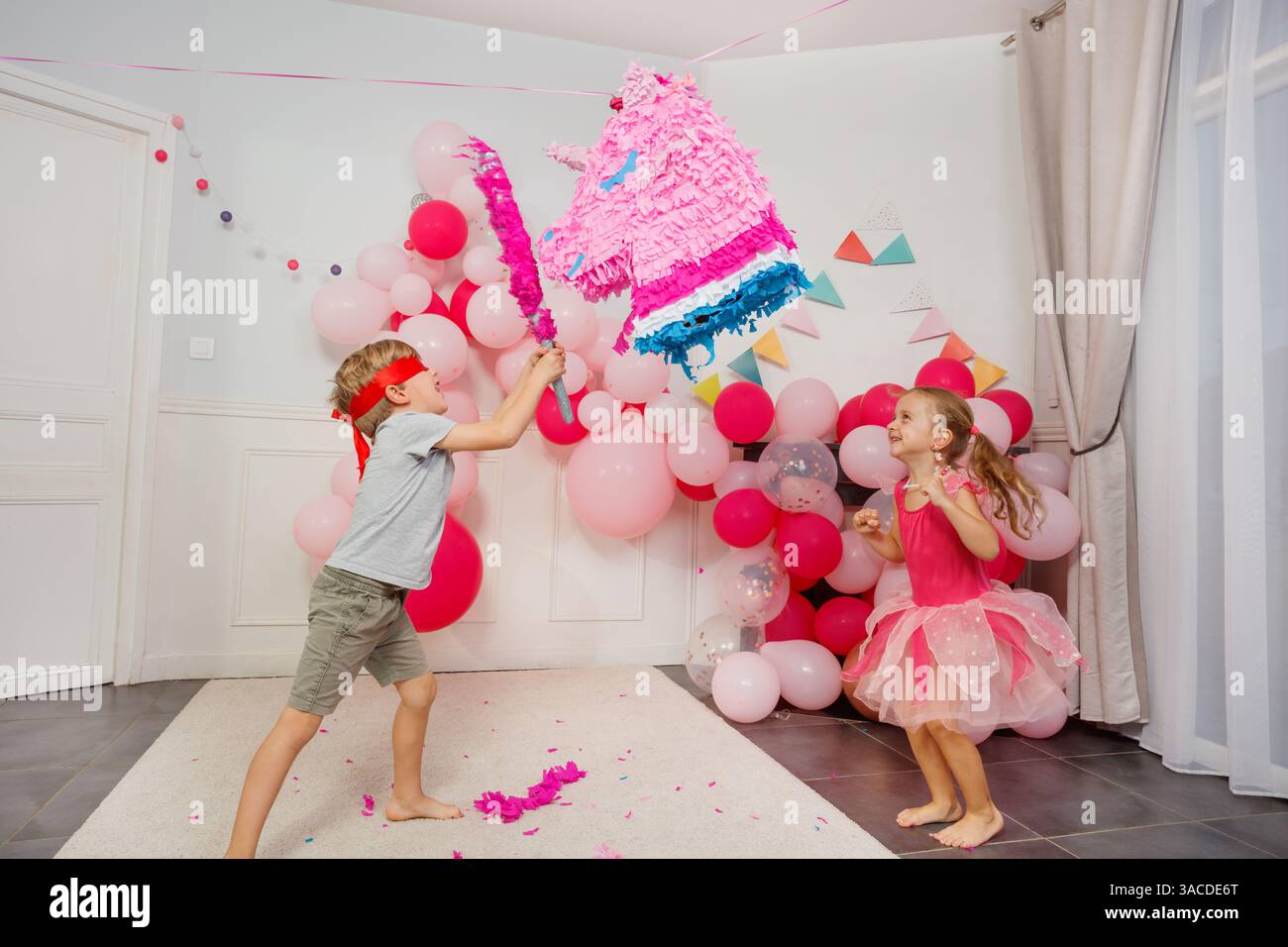 Children laugh and play with a vibrant pinata hitting it hard Stock ...