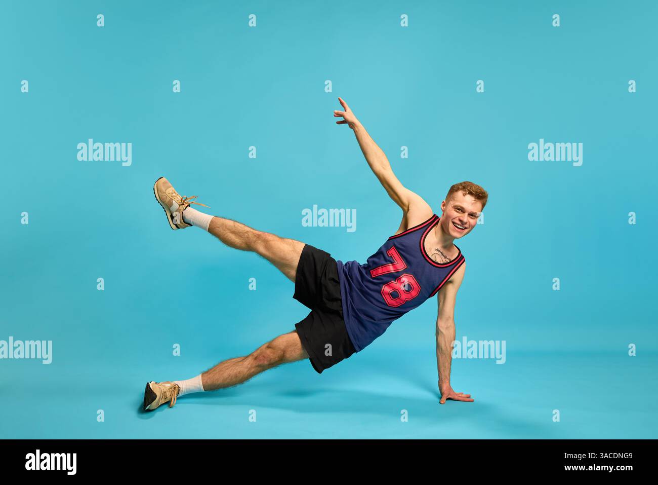 Young man balancing on one hand with lifted leg, smiling and focused ...