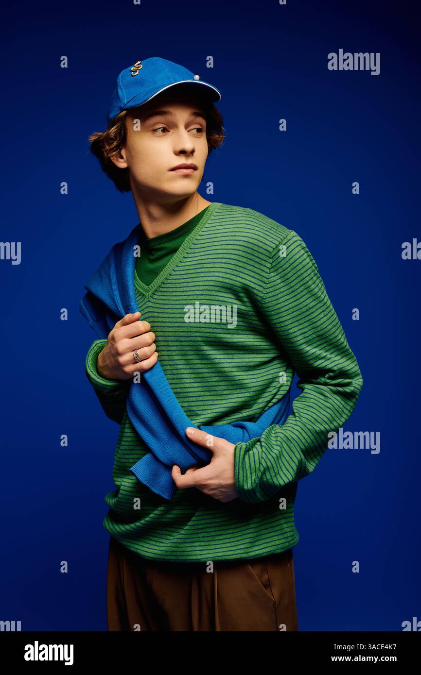 Fashion forward young man poses confidently in stylish attire against a striking blue backdrop ...