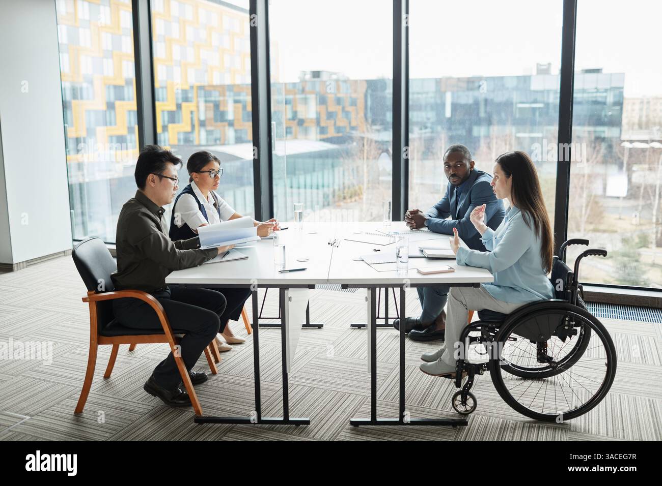 Wide angle view at diverse business team discussing project at table in modern office with focus ...