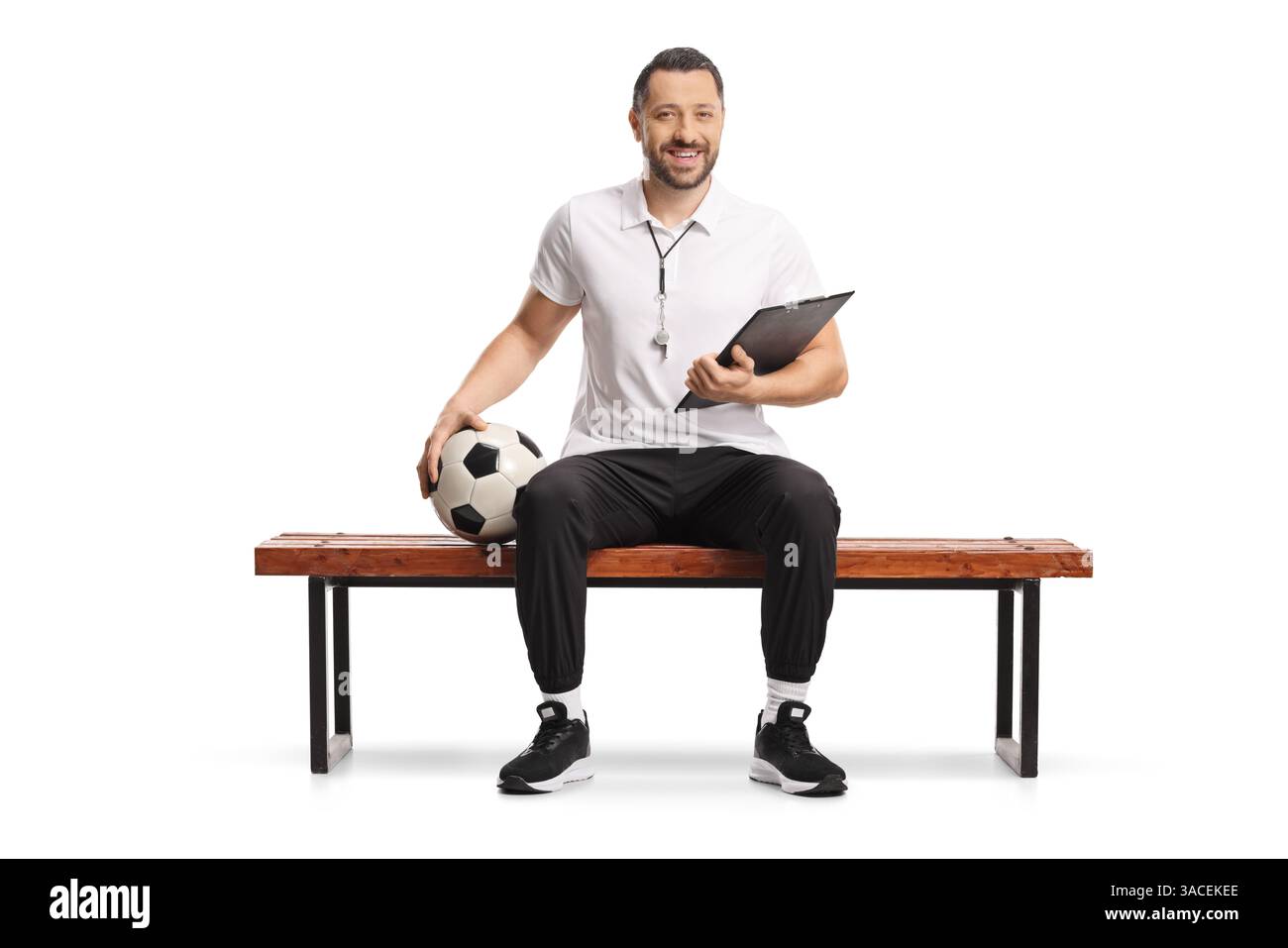 Football coach sitting on a bench with a ball and smiling isolated on ...