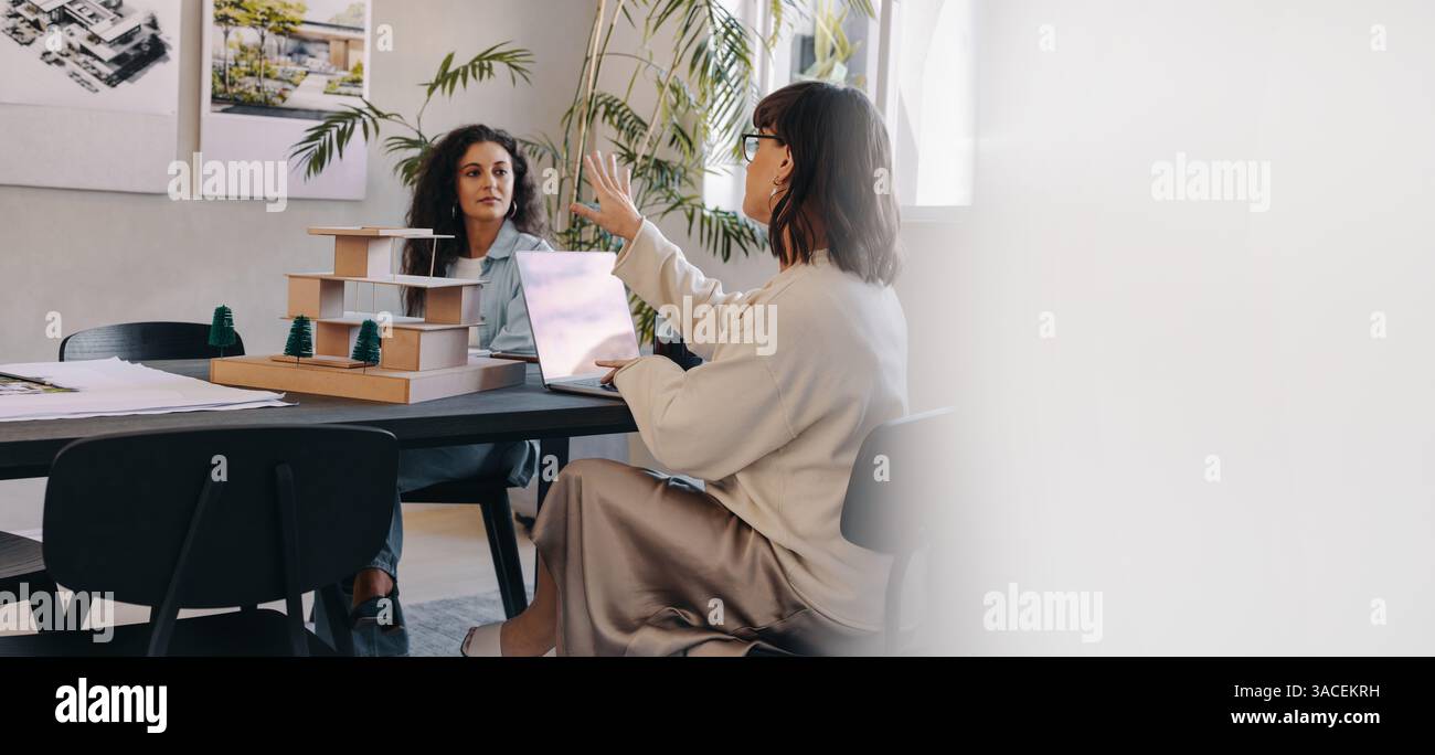 Two female professionals engage in a project management discussion in a ...