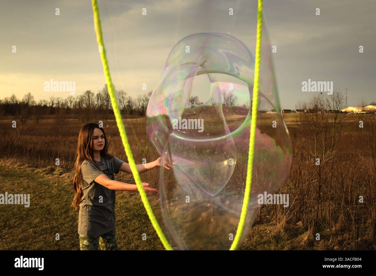 Tween girl popping giant bubble in sunny field Stock Photo - Alamy
