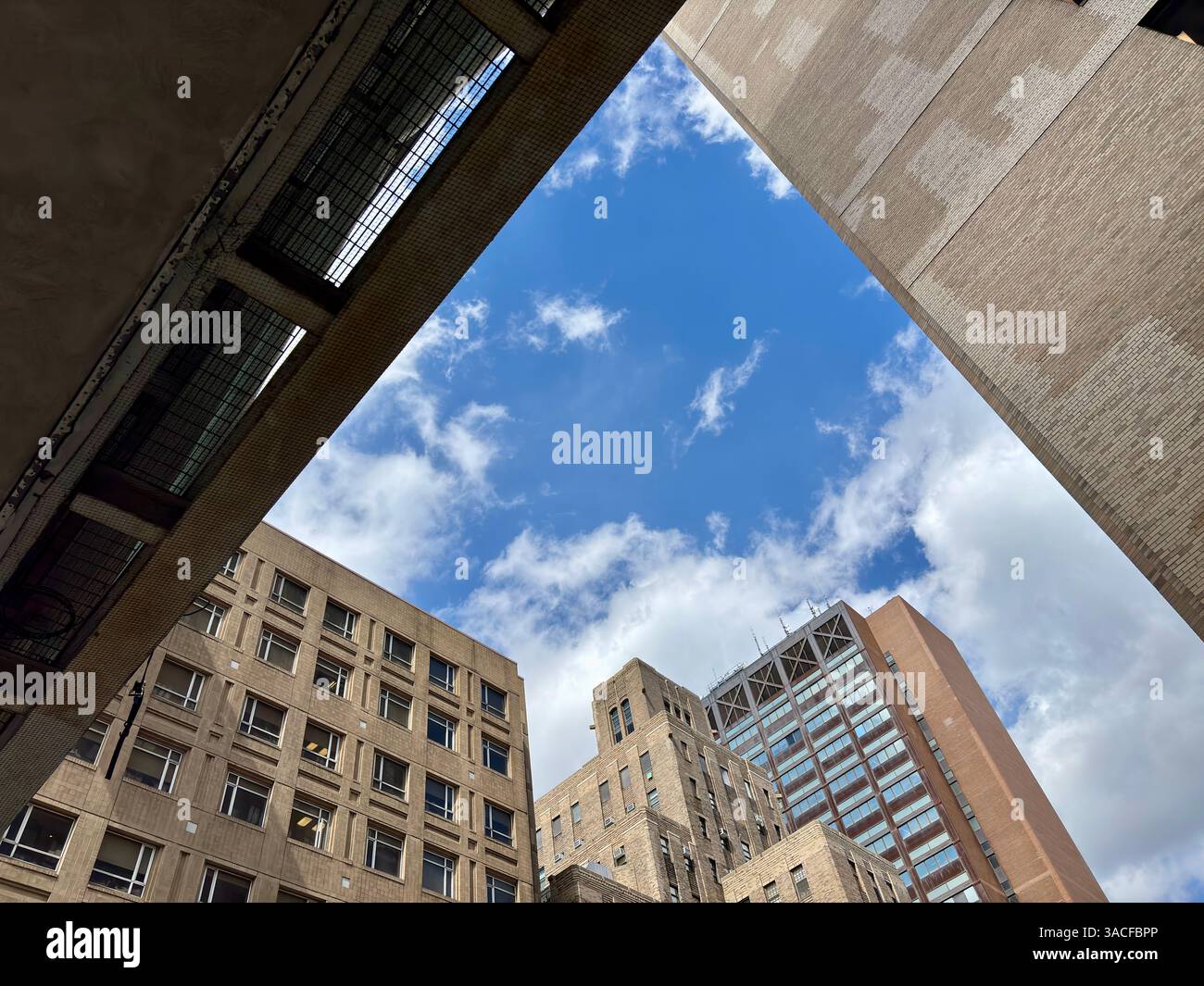 Upward view of urban buildings framing a blue sky with clouds Stock ...