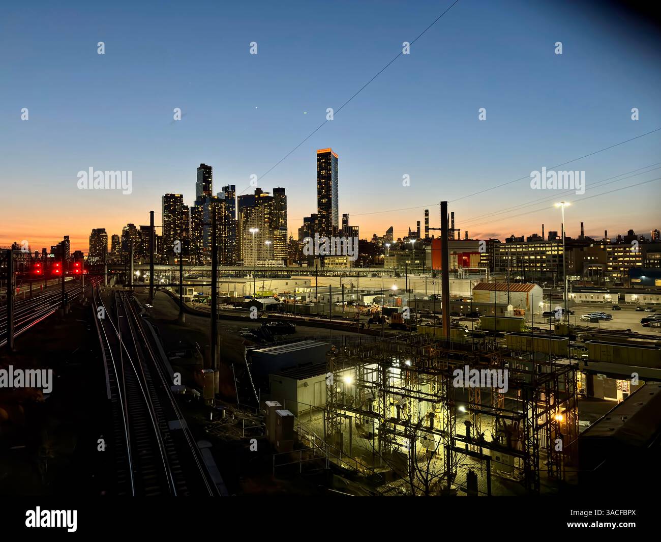 Rail tracks and illuminated scaffolding with city skyline at dusk Stock ...