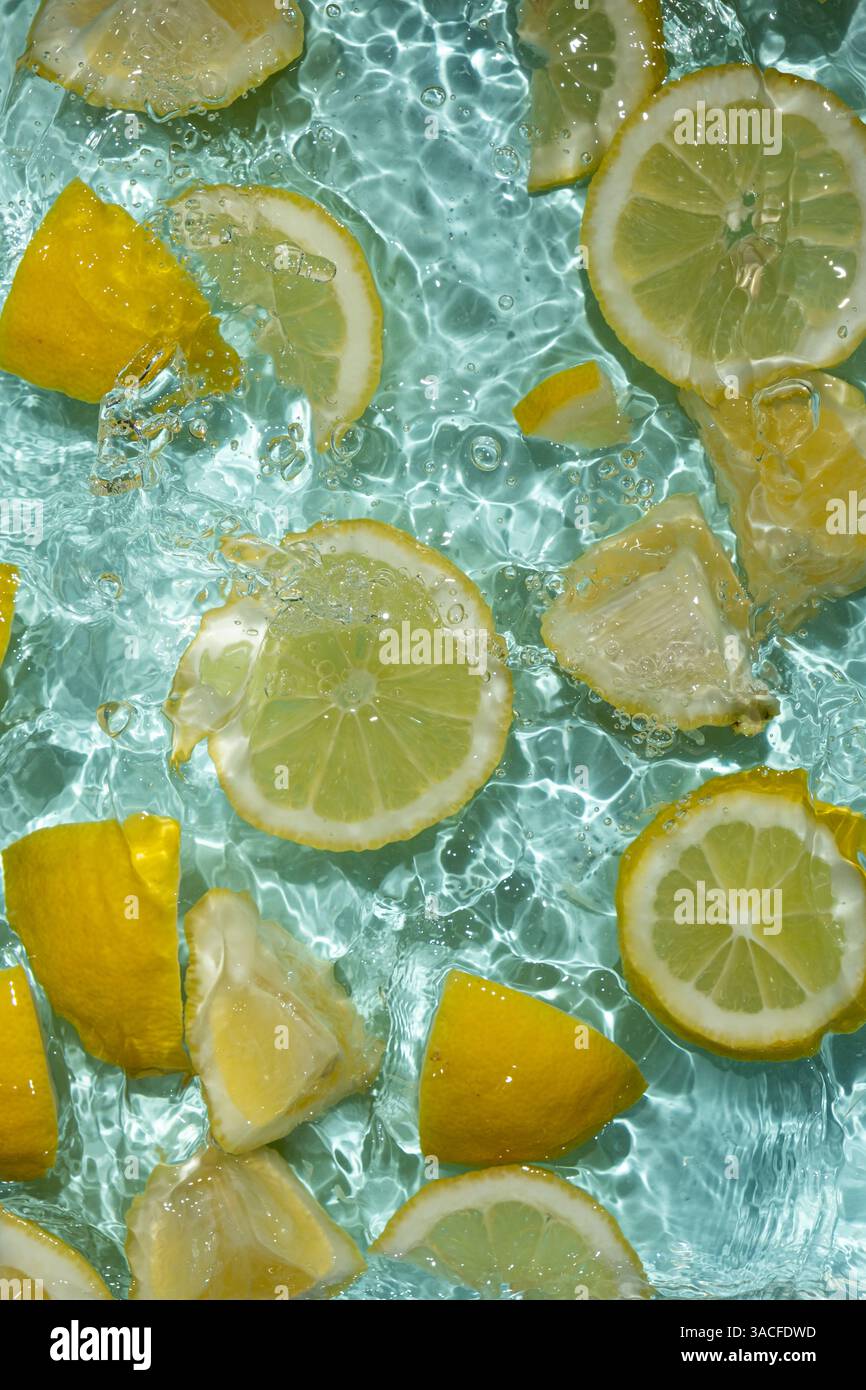 Refreshing turquoise citrus background with floating yellow lemon pieces Stock Photo - Alamy