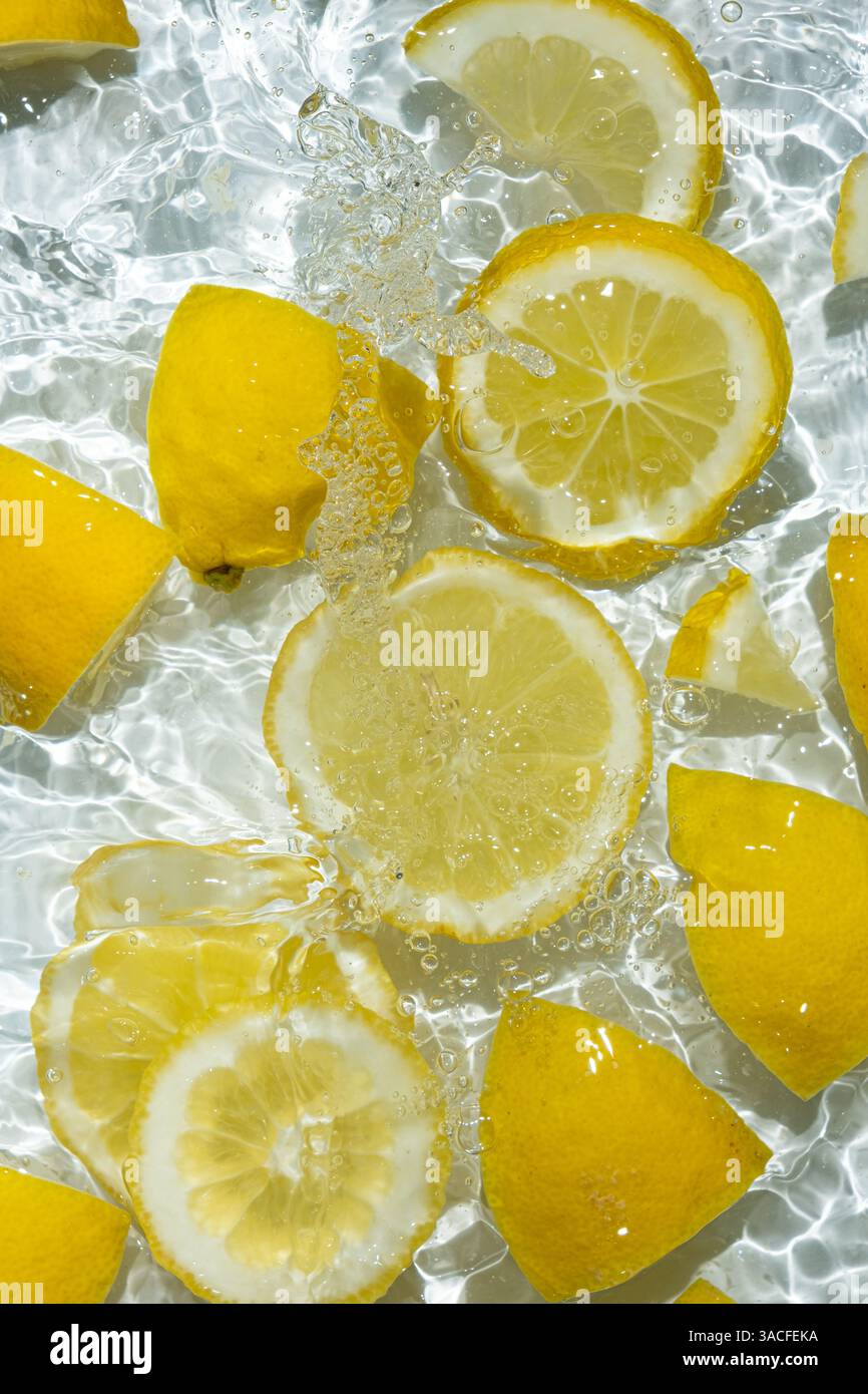 Slices of fresh lemons in water, splash of water, top view Stock Photo ...