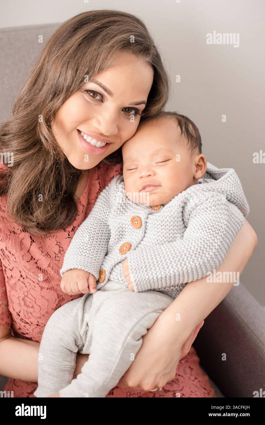 Mother smiling while holding her peacefully sleeping baby Stock Photo - Alamy