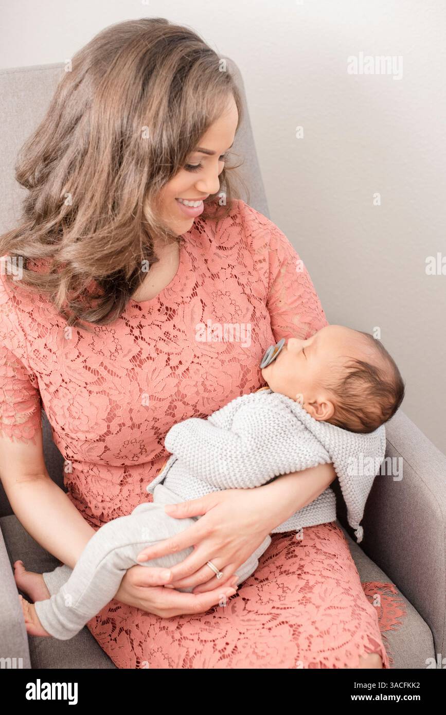 Mother smiles while holding sleeping baby in her arms lovingly Stock ...