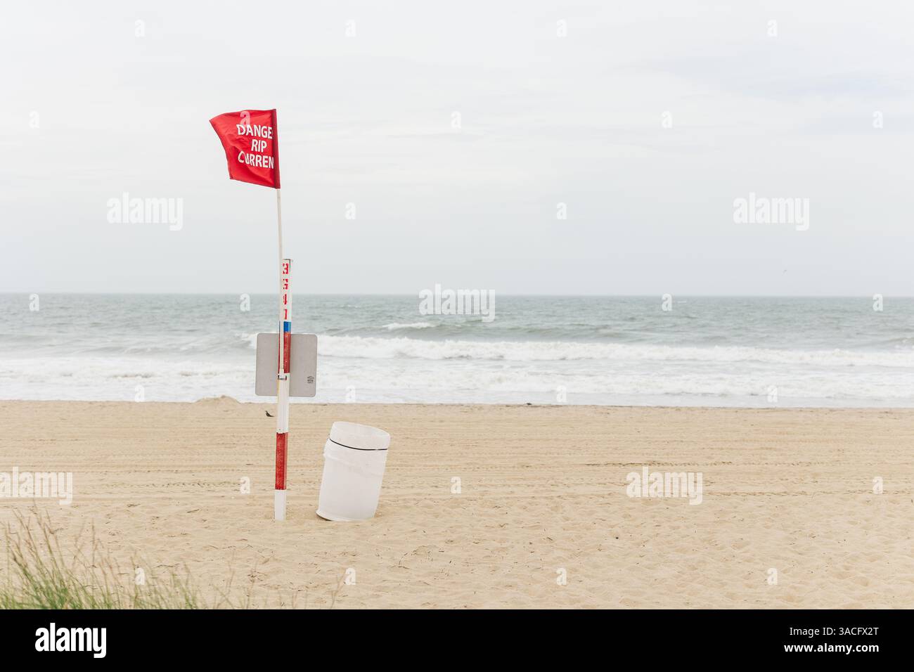 Red warning flag on beach alerts for dangerous rip currents Stock Photo ...