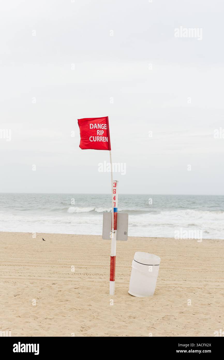 Red warning flag on beach alerts for dangerous rip currents Stock Photo ...
