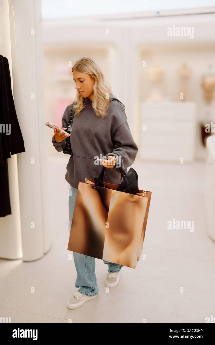 Teen girl with shopping bags checking phone at mall Stock Photo - Alamy