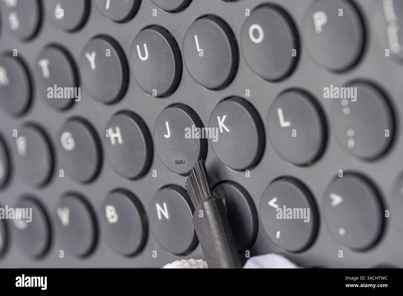 Close up of retro circular keyboard with cleaning brush on letter j key ...