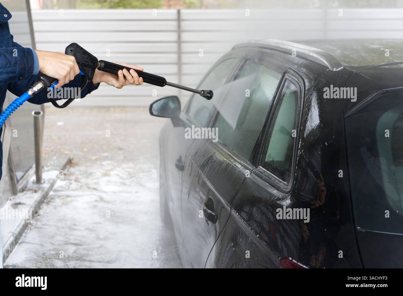 The image shows a person using a high-pressure water hose to clean a ...