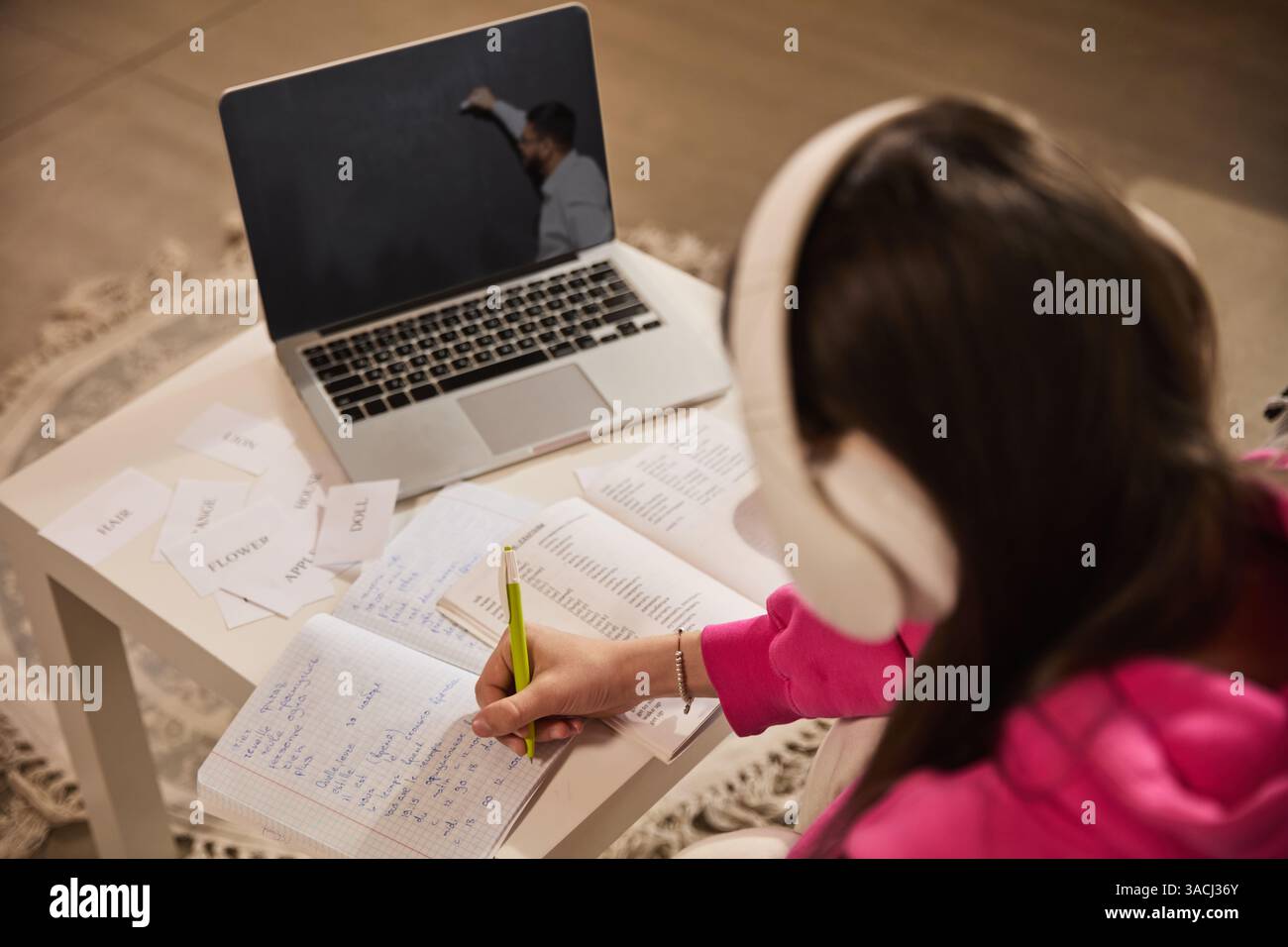 Teen girl in headphones sitting on couch, watching teacher on laptop ...