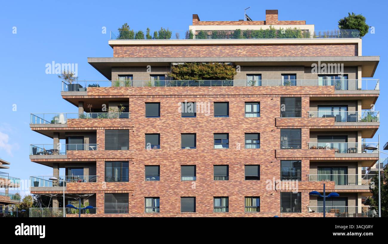 Modern brick residential building featuring balconies, greenery, and ...