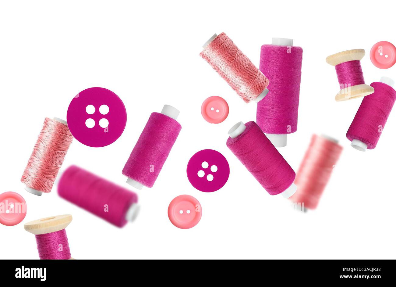 Many sewing threads and buttons in different shades of pink flying on ...