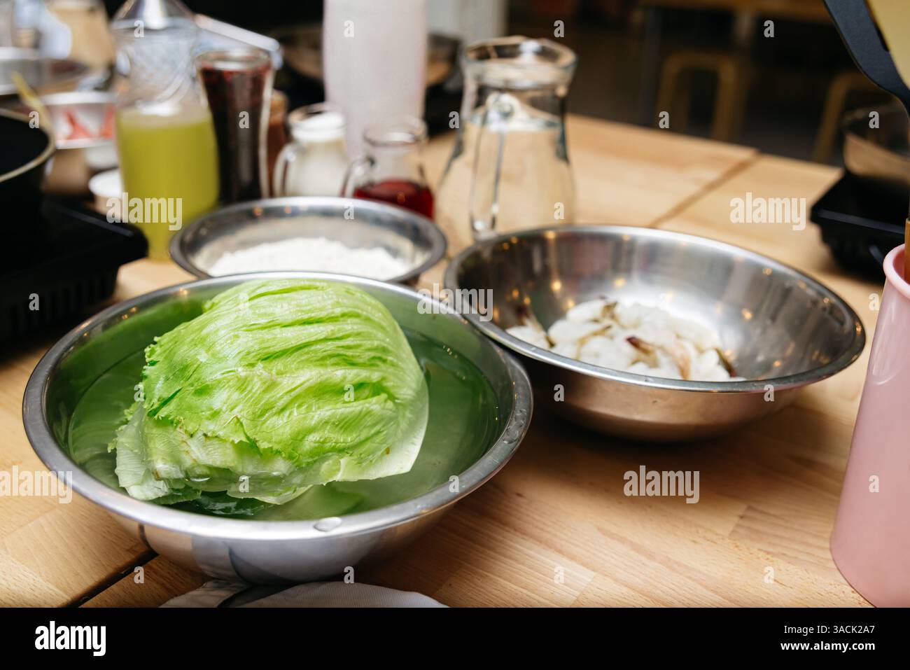 A kitchen counter with fresh iceberg lettuce soaking in water, peeled ...