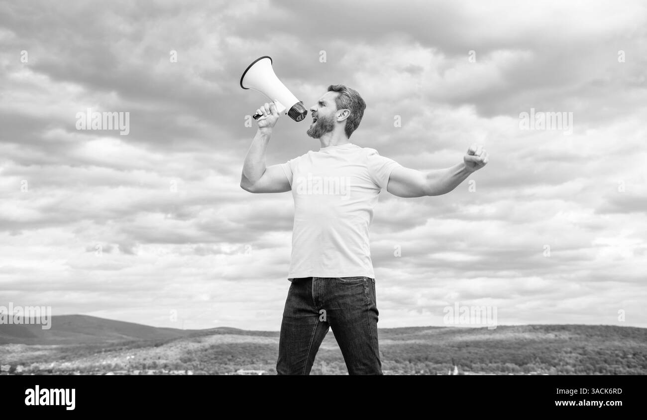 man in yellow shirt announcing in megaphone on sky background Stock ...