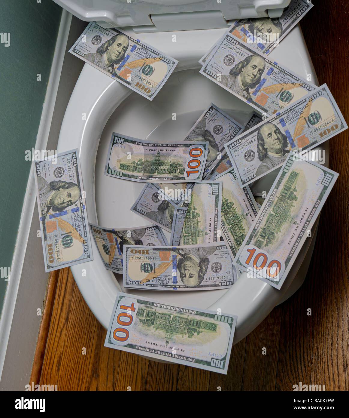 A toilet is filled with money, including hundred dollar bills. A ...