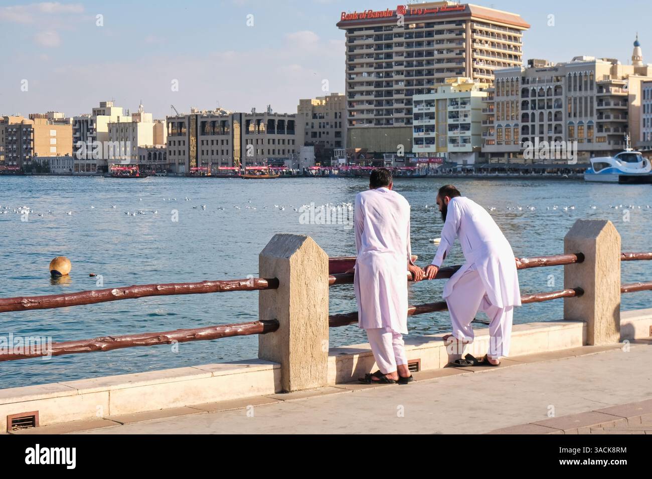 Two middle eastern men wearing traditional cloth overlooking waterfront ...