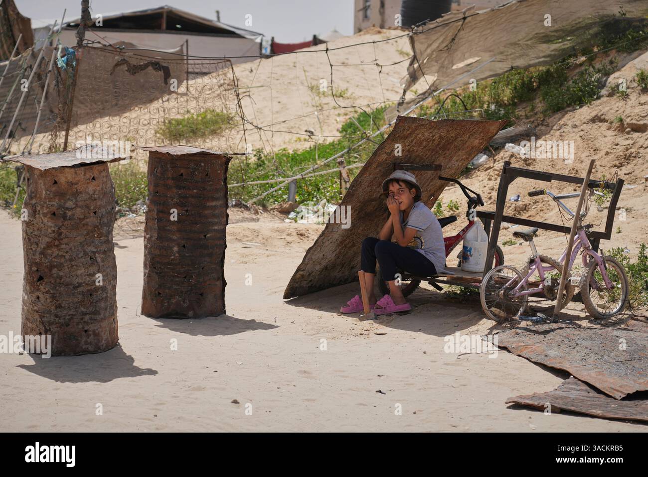 Displaced 12-year-old Rewaa Mukhemer takes cover from the sun as she ...