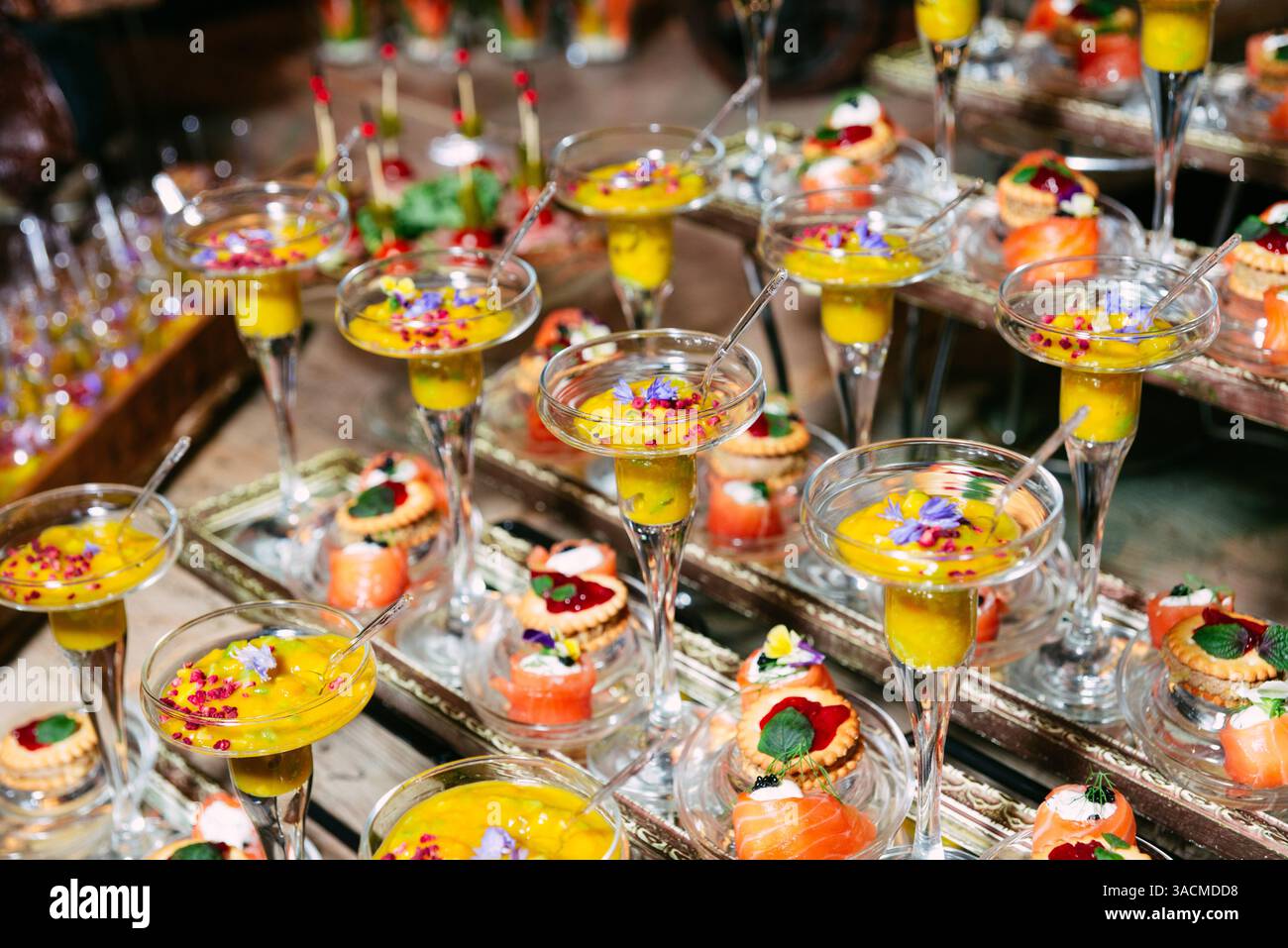 An upscale display of elegant appetizers featuring mango mousse in cocktail glasses and smoked ...