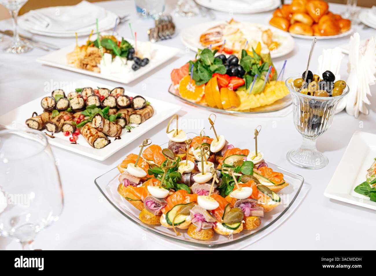 A festive table setting featuring canapés, eggplant rolls, fresh fruits ...