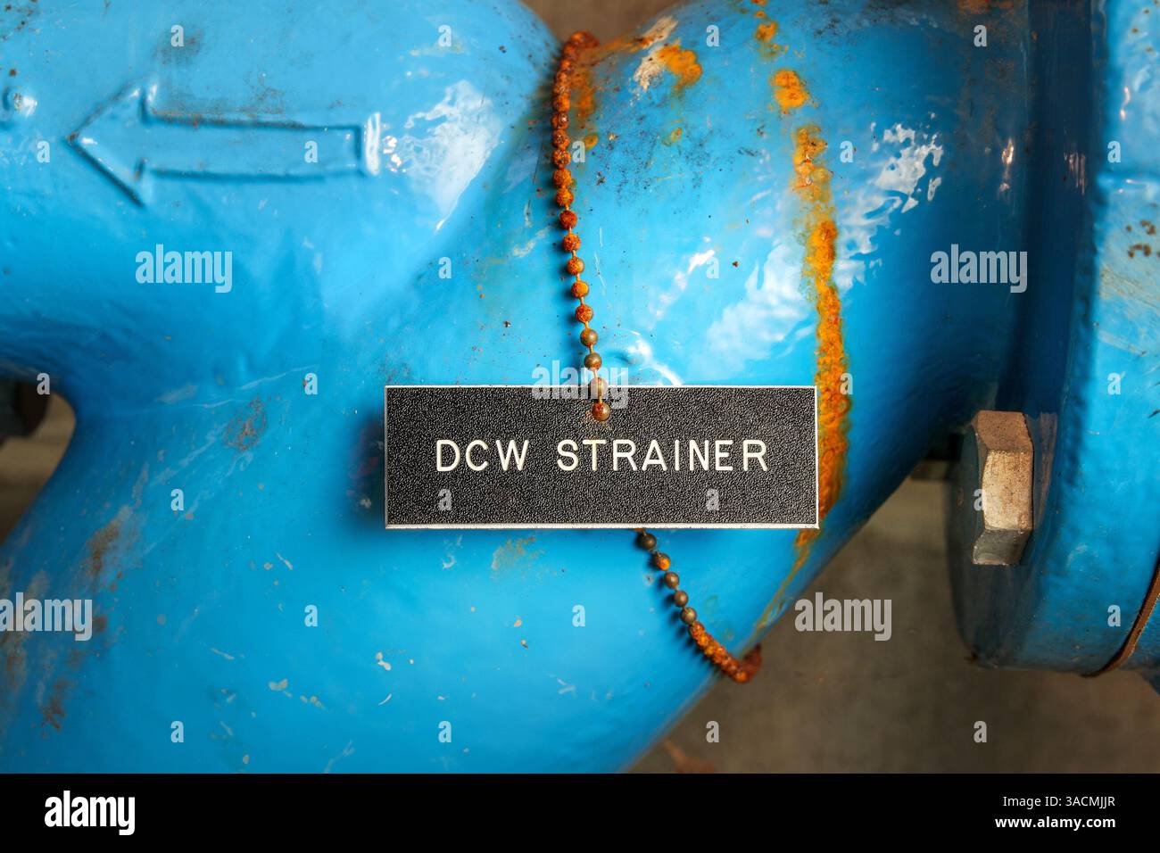 DCW Strainer label on pipe in water meter room. Close up of blue pipe ...