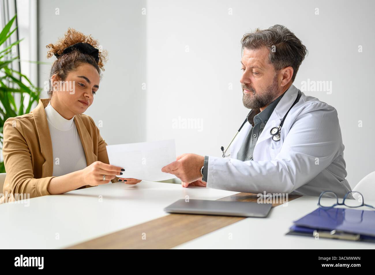 Male doctor showing and discussing medical test results with sad female ...