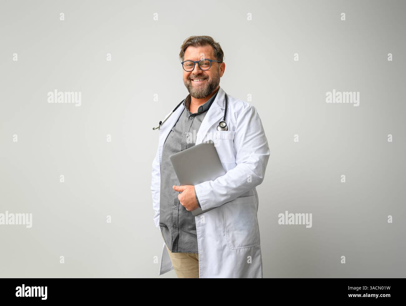 Portrait of confident male doctor in lab coat holding laptop and ...