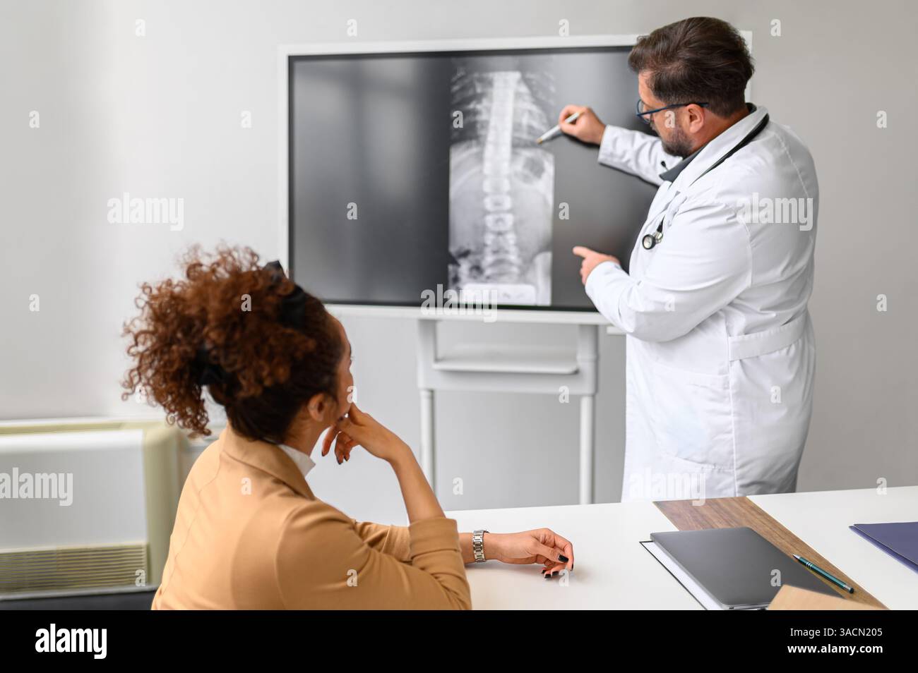 Male radiologist analyzing and explaining x-ray image over computer ...