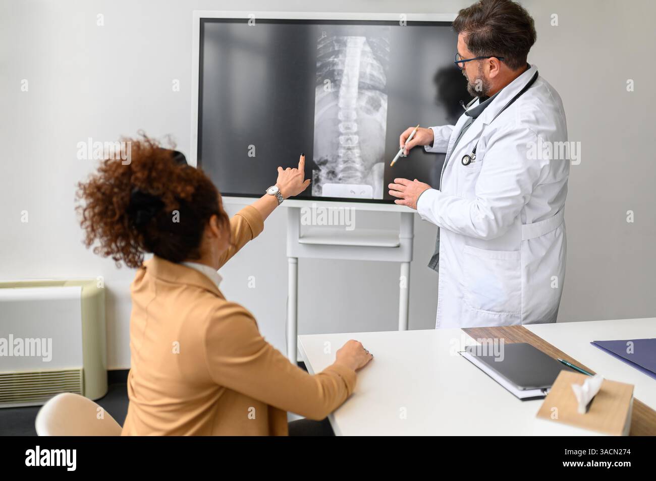 Female patient pointing at x-ray image on computer screen and asking ...