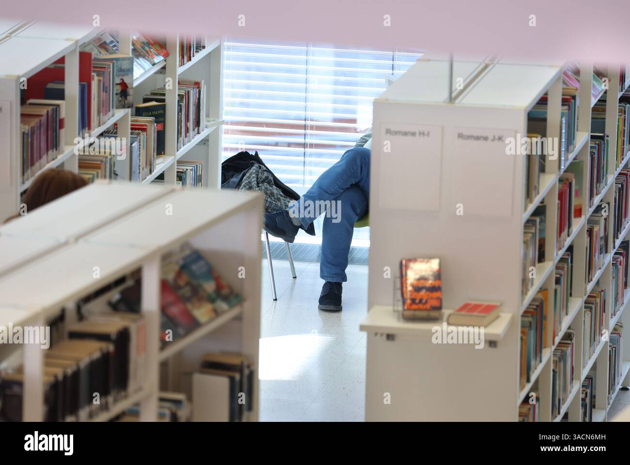 Augsburg, Germany. 04th Apr, 2025. A visitor to the public library sits reading by the window ...